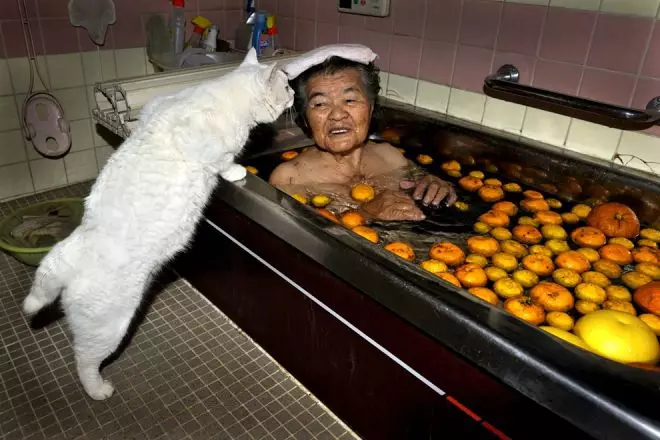 Il gatto sta guardando la nonna prende il bagno