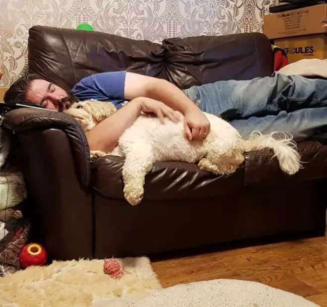 Um homem dorme em um abraço com um cachorro